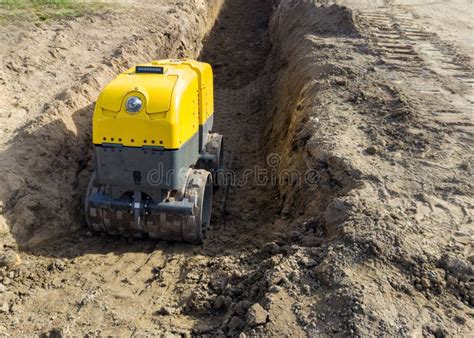 Yellow Trench Compactor Working In A Narrow Trench On Construction Site Stock Image Image Of