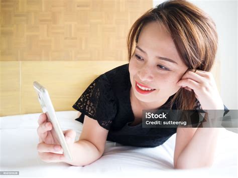 스마트폰 들고와 웃 고 보고 아시아 여 자가 침대에 누워 휴식과 행복 서핑 인터넷의 개념 30 39세에 대한 스톡 사진 및 기타 이미지 30 39세 여자 한 명의