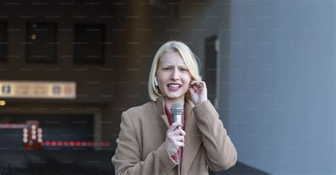 직장에서 전문 여성 기자의 자른 초상화 마이크를 손에 들고 거리에 서서 카메라를 향해 웃고 있는 젊은 여성 수평 촬영 여성에 대한 선택적 초점 사진 Unsplash