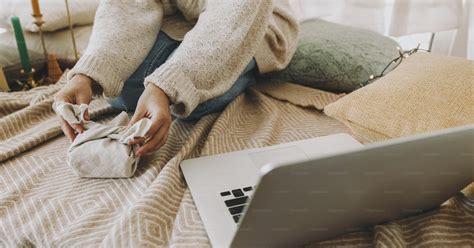 크리스마스 보자기 선물 포장 린넨 패브릭으로 선물을 포장하는 여성 손은 노트북 온라인 자습서로 축제 장식 보헤미안 룸에서 닫힙니다 제로 웨이스트 친환경 휴가 사진