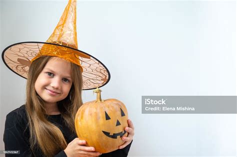잭 오 랜턴 얼굴과 호박을 들고 마녀 의상을 입은 어린 소녀의 초상화 집에서 할로윈을 준비하는 오렌지 모자를 쓴 아이 가족 휴가 파티 텍스트 공간 복사 10월에 대한 스톡