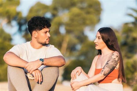 Joven Pareja Latina Sentada En Un Parque Mientras Habla Durante La Puesta De Sol En Verano