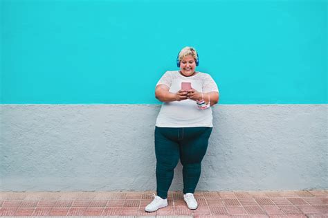 스마트 폰과 아름다운 매력적인 여자는 재생 목록에서 음악을 즐길 수 해피 통통한 소녀와 기술 트렌드 개념 플러스 사이즈 모델에 대한 스톡 사진 및 기타 이미지 Istock