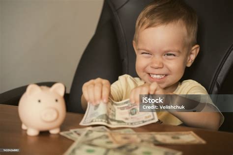 돼지 저금통 근처에서 달러 지폐를 보유한 어린이 돼지 저금통에서 돈을 저축하고 저축에 대해 배우는 똑똑한 행복한 소년 돈 재정 보험 및 사람 개념 2 3 살에 대한 스톡