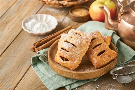 핸드 파이 미니 퍼프 페이스 트리 또는 사과로 채워진 핸드 파이와 나무 접시에 설탕 가루를 뿌린다 아침 식사를위한 빵 껍질과 수제 파이 스낵 소박한 사진 공간을 복사합니다