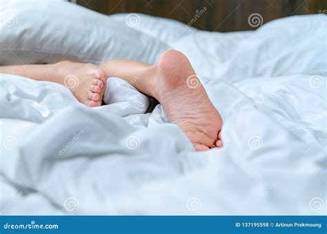 Close Up Woman Bare Feet On The Bed Over White Blanket And Bed Sheet In