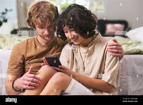 Young Attractive Woman Scrolling Through Online Goods In Smartphone While Sitting On The Floor