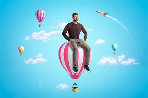 다른 열기구와 배경에 로켓과 푸른 하늘에 분홍색과 흰색 열기구의 상단에 앉아 심각한 젊은 남자 개념에 대한 스톡 사진 및 기타 이미지 Istock