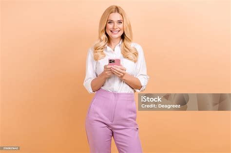 긍정적 인 경험 성숙 한 여자 금발 머리를 입은 세련된 정장 착용 스마트 폰을 사용하여 베이지 색 배경에 고립 된 사진 40