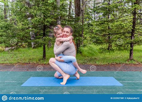 Mother And Daughter Doing Yoga On Grass In The Park At The Daytime