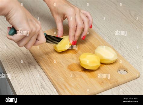Housewife Cuts Potatoes In Half On A Kitchen Board Peeling Potatoes