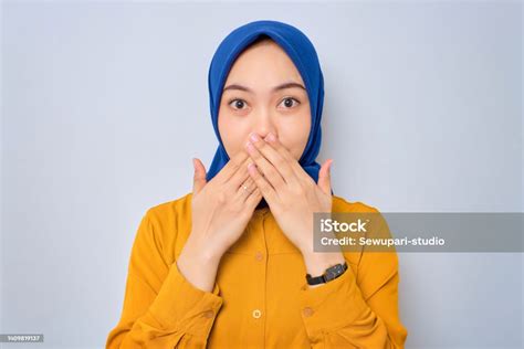 오렌지색 셔츠를 입은 젊은 아시아 무슬림 여성이 하얀 배경에 고립 된 실수로 손으로 입을 가리고 충격을 받았습니다 20 24세에 대한 스톡 사진 및 기타 이미지 Istock
