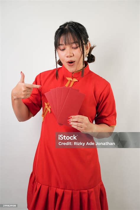 빨간 전통 중국 드레스를 입고 웃는 젊은 아시아 여성은 흰색 배경 위에 고립 된 많은 빨간 봉투를 들고 있습니다 음력 설날 파티에 대 한 개념 12월 31일에 대한 스톡