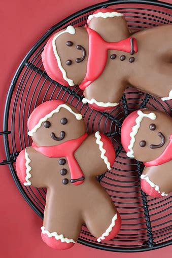 수제 아버지 크리스마스의 원형 냉각 랙의 전체 프레임 이미지 빨간색과 흰색 로얄 아이싱 산타 모자 빨간색 스카프 빨간색 배경 쿠키 3 개 높은 전망으로 얼어 붙은 초콜릿