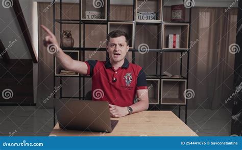 Friendly Man At Table With Laptop Is Speaking Looking At Camera Stock Footage Video Of