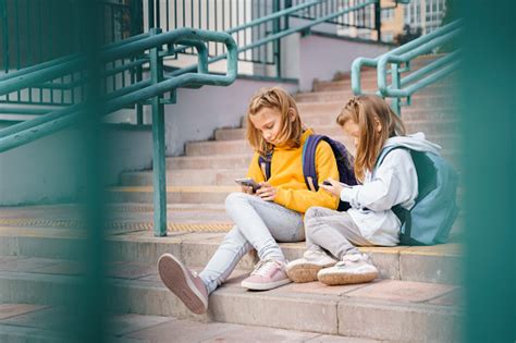 초등학교 초등학교로 돌아 가기 배낭 휴대 전화를 가진 어린 소녀 소셜 미디어에서 서핑 채팅 친구와 이야기 휴식 시간에 급우 방학