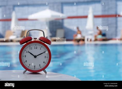 Red Analog Alarm Clock With Blurred Background Of Relaxation Pool Stock