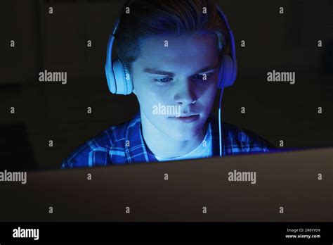 Teenage Boy In Headphones Using Computer At Night Internet Addiction