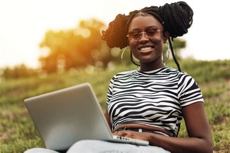 African American Female Student Sitting In Park Working On Laptop