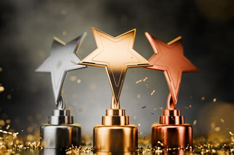 금빛 반짝이의 우승자를 위한 장소 우승자 컵은 대회에서의 승리와 성공을 상징하는 축제 색종이 조각으로 둘러싸여 있습니다 우승자에게는 금 은 동메달 컵이 수여됩니다 1위에