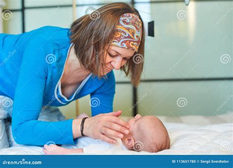 Мать и ребенок на белой кровати Мама и ребёнок в пеленке играя в