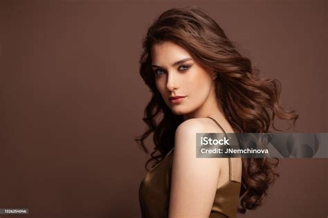 갈색 배경에 완벽한 피부와 긴 어두운 곱슬 바람이 부는 머리를 가진 건강한 젊은 여성 갈색 머리에 대한 스톡 사진 및 기타 이미지 갈색 머리 긴 머리 한 명의 여자만