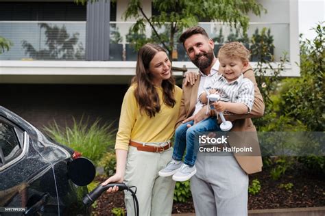 행복한 가족은 차 옆에 서서 거리에서 전기 자동차를 충전합니다 전기 자동차 대체 연료 자동차에 대한 스톡 사진 및 기타 이미지 전기 자동차 대체 연료 자동차 싣기