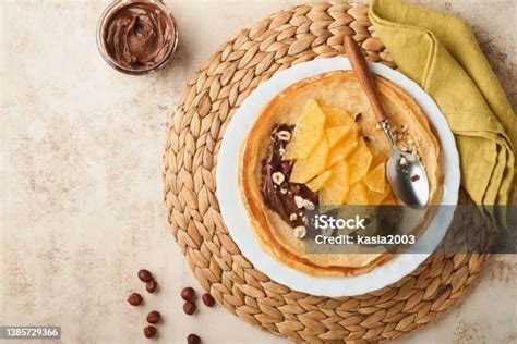 크레페 스게트 와 오렌지 초콜릿 스프레드 헤이즐넛 오렌지 슬라이스 과일을 흰색 접시에 넣고 오래된 콘크리트 소박한 테이블 배경에서 아침 식사를 하는 얇은 크레페 복사 공간을