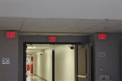 Three Exit Signs Illuminated In Hallway