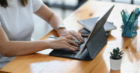 나무 워크스테이션에서 태블릿 컴퓨터로 작업하는 젊은 여성 조직자의 모습을 닫습니다 사진 Unsplash의 태국 이미지