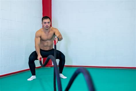 체육관에서 운동을 위해 배틀 로프를 사용하는 잘 생긴 근육질의 청년의 이미지 그는 운동 수행에 중점을 둡니다 동기 부여 사진