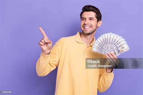쾌활한 사람의 사진 이빨 미소 손 잡고 달러 지폐는 보라색 배경에 고립된 직접적인 손가락 빈 공간을 본다 25 29세에 대한