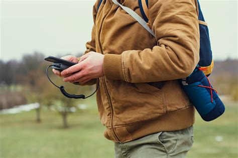 관광객은 손에 스마트 폰휴대용 충전기를 들고있다 녹색자연의 배경에 남자 Usb 케이블에 대한 스톡 사진 및 기타 이미지 Usb 케이블 Usb 포트 개념 Istock