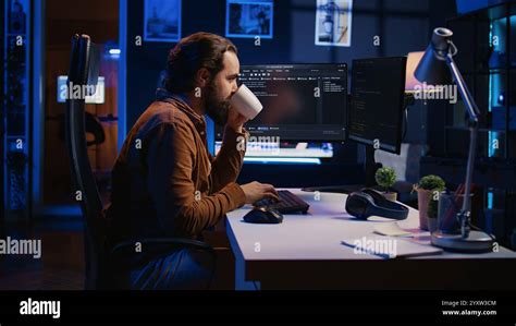 Focused Programmer Drinking Coffee In Apartment While Solving Database