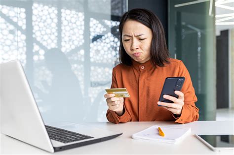 직장에서 사무실 안에서 화가 나고 실망한 여성 은행 신용 카드와 전화를 들고 바람을 피우는 아시아 여성 비즈니스 여성이 거부 및 송금 오류를 겪었습니다 신용 카드에 대한