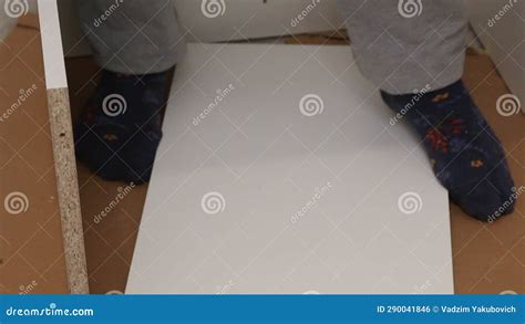 A Man Is Assembling A Bookshelf Attaches The Side Walls With A Key