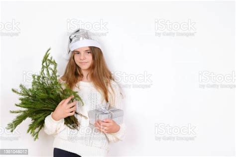 흰색 스웨터와 실버 산타 모자를 입은 어린 소녀는 선물과 크리스마스 나무 가지를 직접 보입니다 10 11세에 대한 스톡 사진 및 기타 이미지 Istock