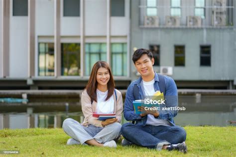 캠퍼스 잔디에 앉아 카메라를 보고 미소를 짓고 공원에서 책 토거터를 읽는 아시아 남자와 여자 대학생의 초상화 20 24세에 대한 스톡 사진 및 기타 이미지 Istock