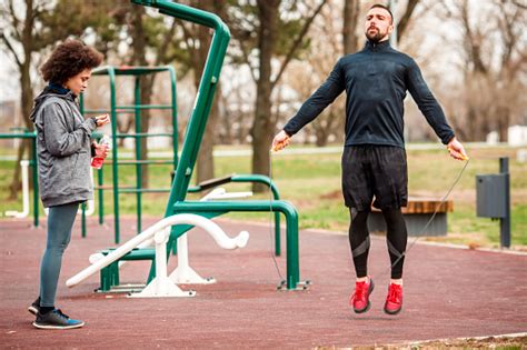 그의 옆에 서 있는 여성 코치와 스톱 워치와 시간을 측정 하 여 공공 공원에서 점프 로프 운동을 하는 남성 선수 2명에 대한 스톡 사진 및 기타 이미지 Istock