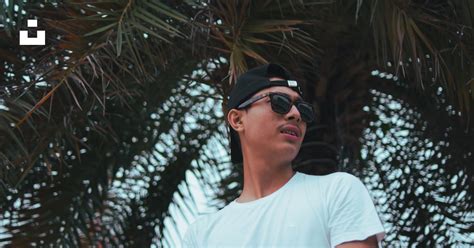 흰색 크루넥 티셔츠를 입은 남자가 녹색 야자수 근처에 서 있는 동안 검은색 선글라스를 끼고 있다 사진 Unsplash의 무료 벽 종이 이미지