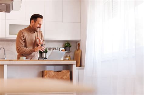 부엌에서 일하는 동안 노트북에서 화상 통화로 몸짓하고 설명하는 자신감 넘치는 남성 프리랜서 가정 생활에 대한 스톡 사진 및 기타 이미지 가정 생활 가정 주방 가정의