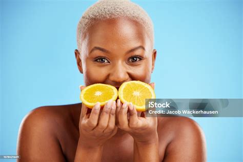 초상화 아름다움 과일은 자연의 건강을 위해 파란색 배경에 스튜디오에 있는 모델 흑인 여성과 함께합니다 얼굴 스킨케어 오렌지와 함께 행복한 젊은 여성이 건강을 위해 신선한