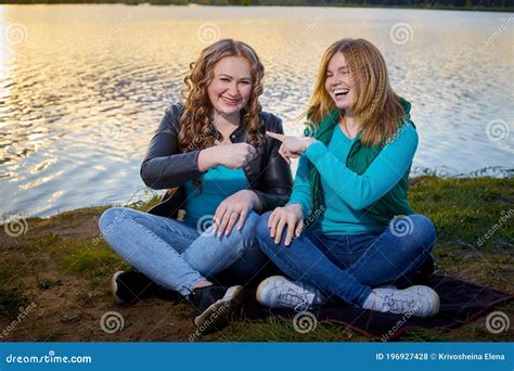 Two Girls Friends Sisters Cousins Socializing And Having Fun On The Shore Or Beach Of A Lake