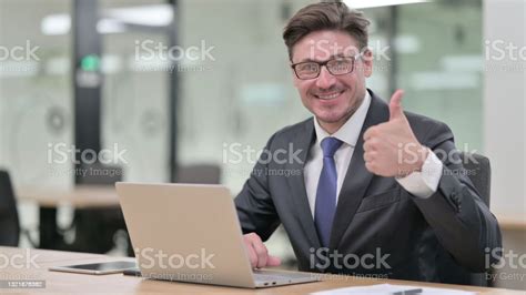 사무실에서 일하는 긍정적 인 중년 사업가에 의해 엄지 손가락 40 49세에 대한 스톡 사진 및 기타 이미지 40 49세