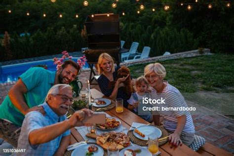 뒤뜰에서 함께 즐거운 시간을 보내는 행복한 사람들 식탁에서 전화를 통해 셀카를 찍는 3대 가족 뒤뜰에 대한 스톡 사진 및 기타 이미지 Istock