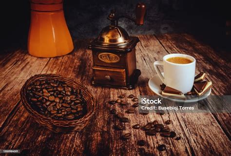 골동품 금속과 나무 손 커피 그라인더와 어두운 배경에 오렌지 이탈리아 커피 냄비와 나무에 초콜릿과 흰색 컵 바구니에 구운 커피