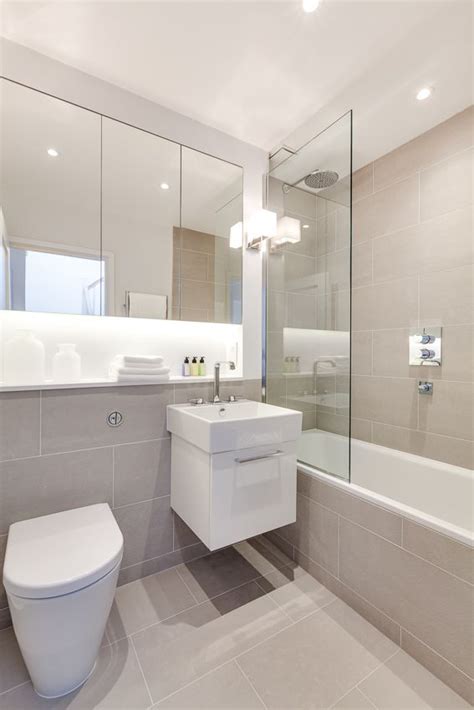 A White Toilet Sitting Next To A Bath Tub Under A Bathroom Mirror Above