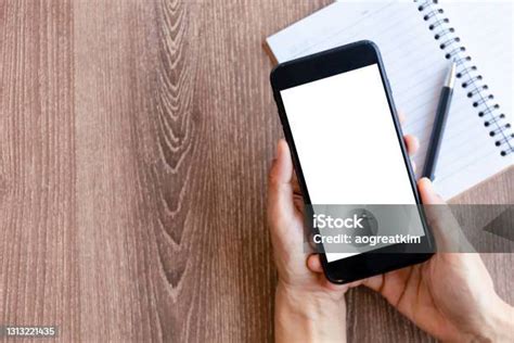 상단 보기 여성 손 빈 흰색 화면과 스마트 폰을 들고 여성은 작업 공간을 손 나무 테이블 배경에 텍스트와 내용에 대한 스마트 폰 빈 화면을 들고 클로즈업 스마트폰에 대한