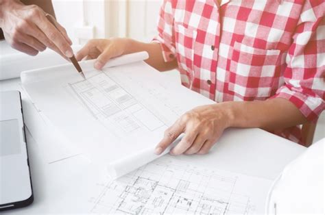 Premium Photo Midsection Of Colleagues Analyzing Blueprints On Office Desk