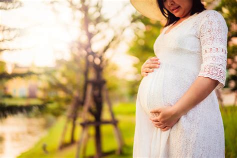 임산부는 아이를 돌보면서 정원에서 새로운 삶에 행복을 느낍니다 임신 한 배에 아기를 들고 젊은 기대 어머니 출산 전 관리 및
